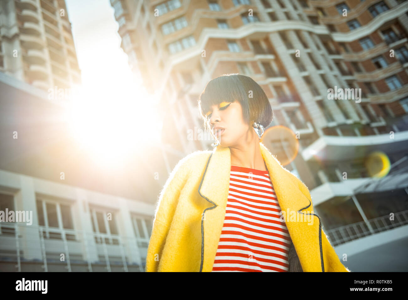 Neglectful appealing girl closing eyes because of bright sun lights ...