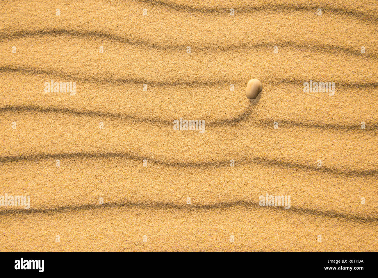 Sand of a beach with pebble and wave patterns Stock Photo - Alamy