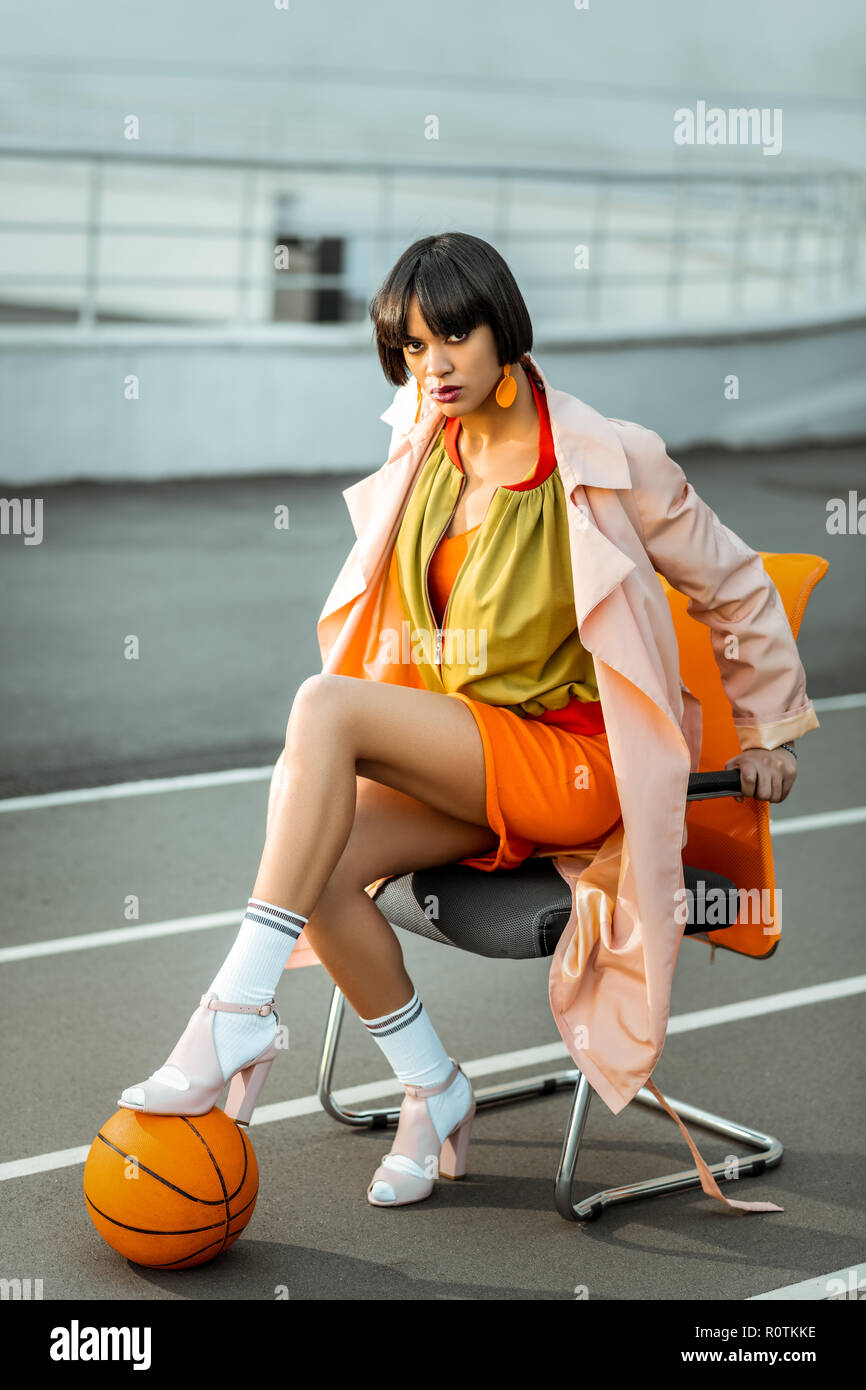 Resolute strong woman stepping on the ball wearing light pink cloak ...