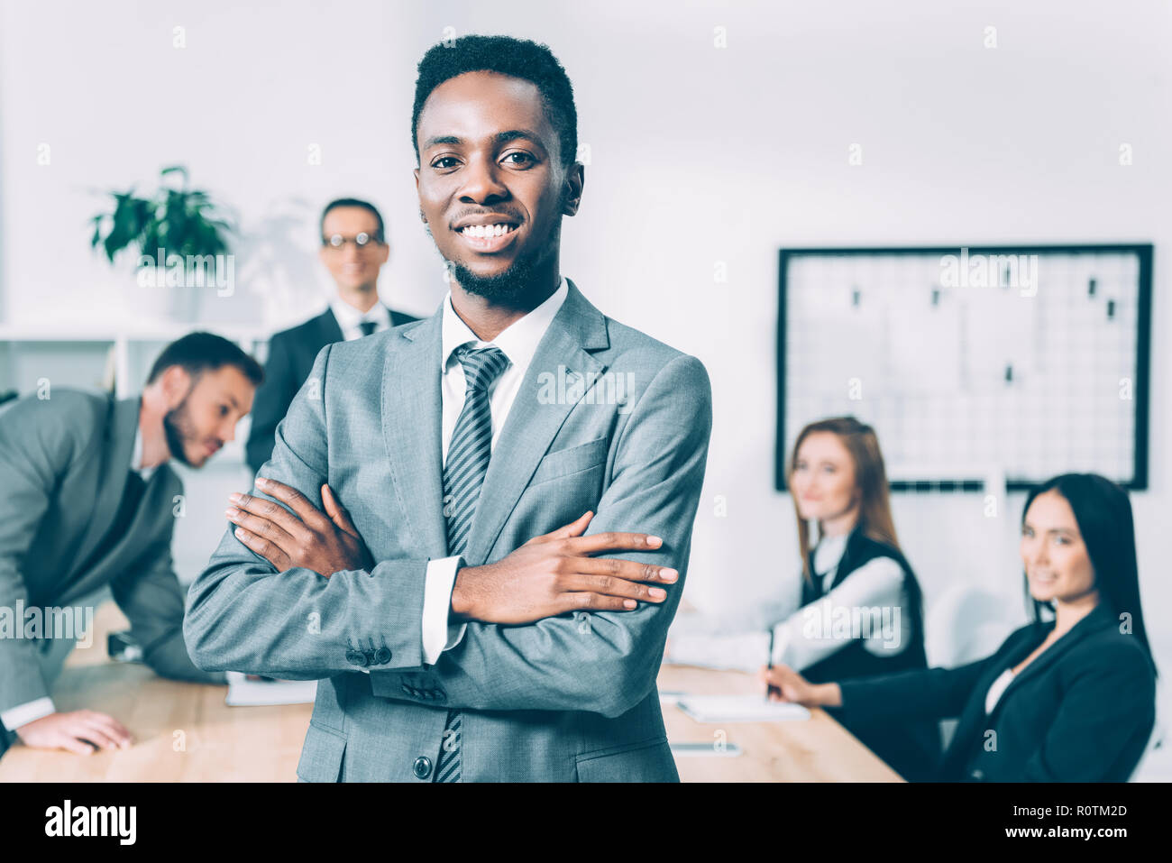 handsome african american manager with crossed arms with blurred ...