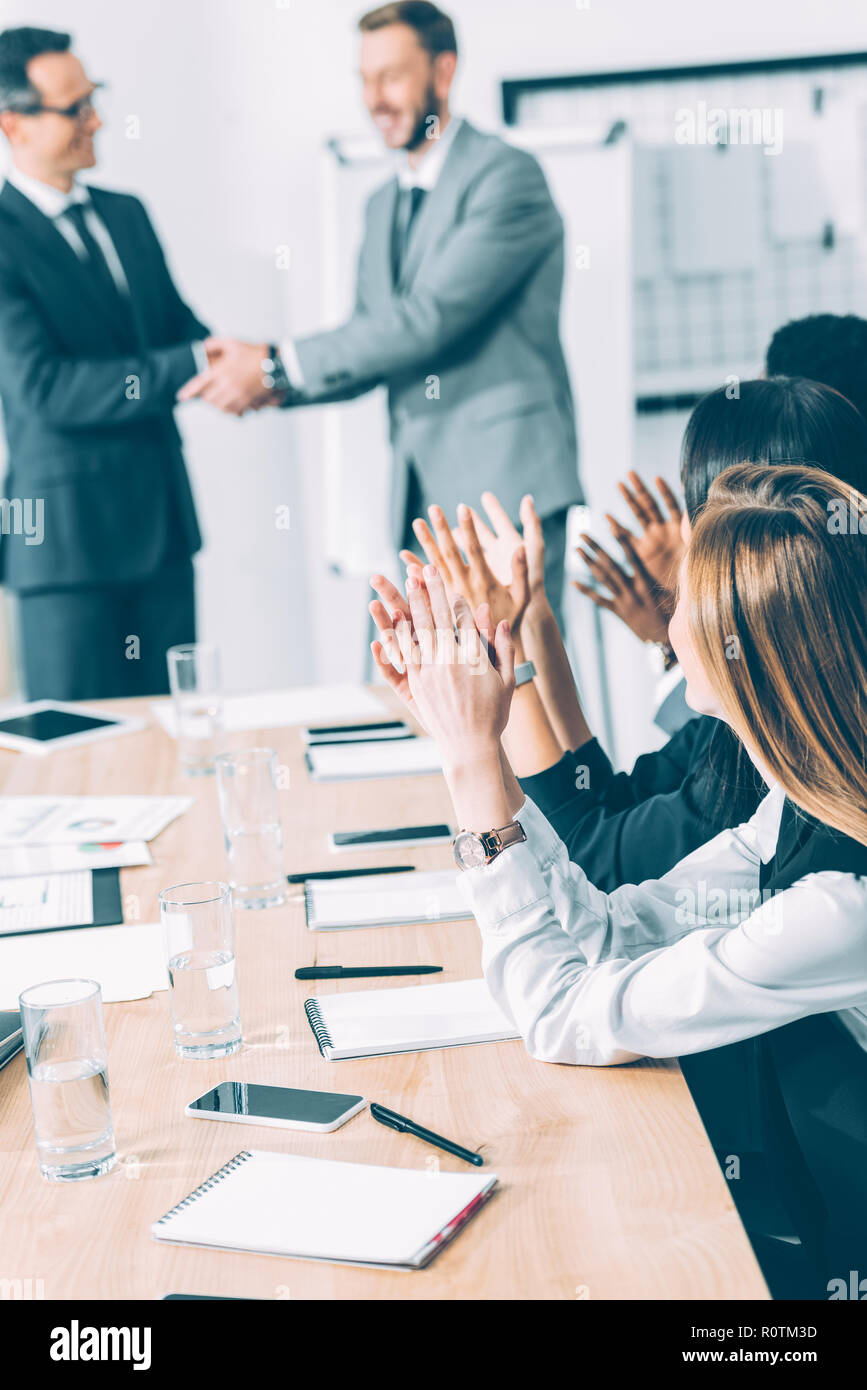 boss shaking hand of manager while colleagues clapping in conference ...