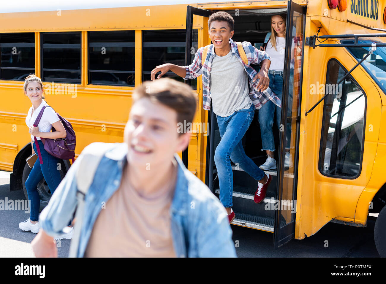 group of happy teen scholars running out school bus Stock Photo - Alamy
