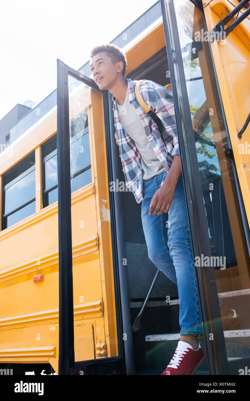 bottom view of happy teen african american schoolboy walking out school ...