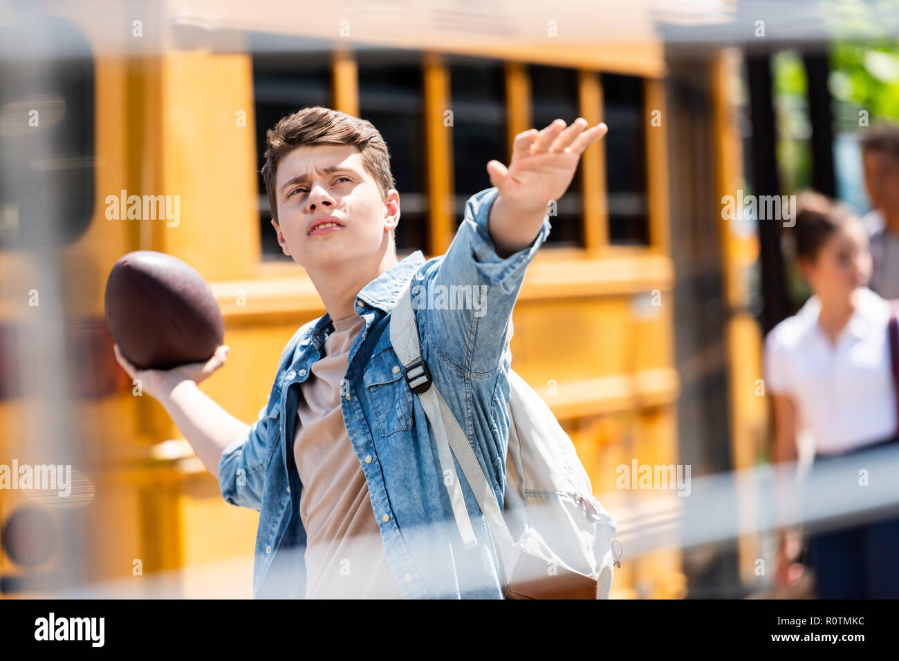 sporty teen schoolboy throwing american football ball in front of ...