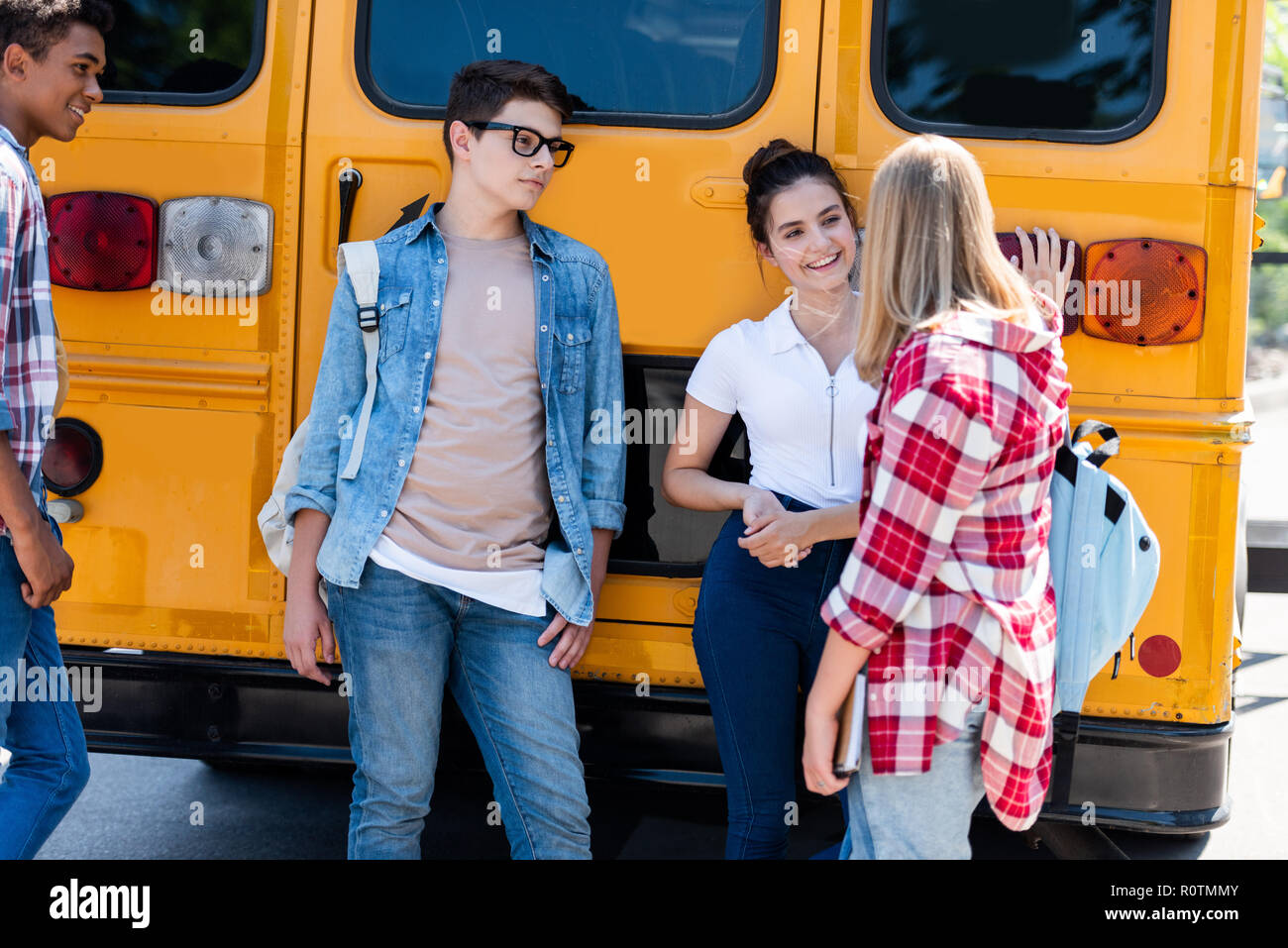 group of teen scholars talking while leaning on school bus Stock Photo ...