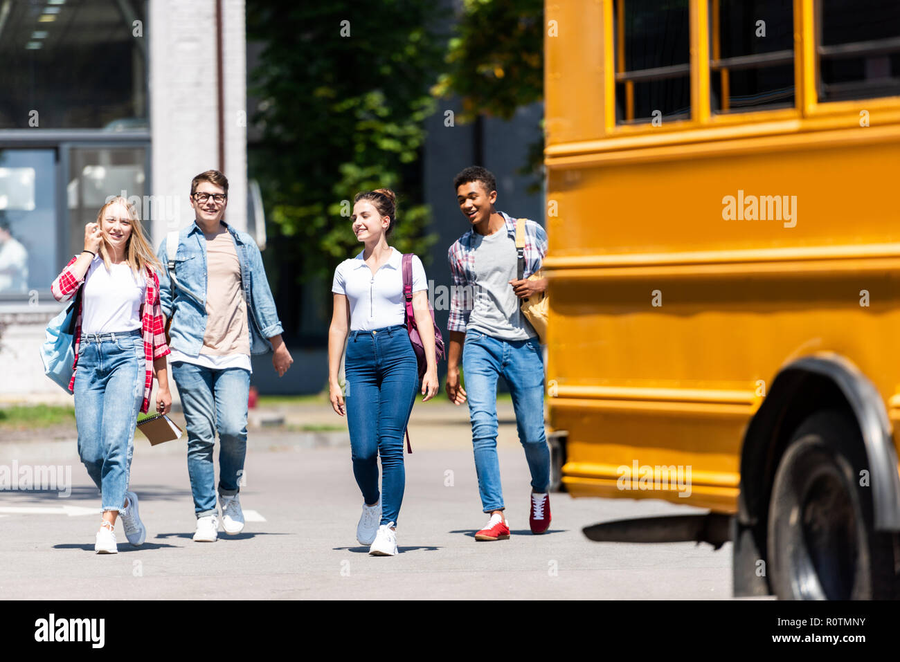 group of teen scholars walking behind school bus on parking Stock Photo ...