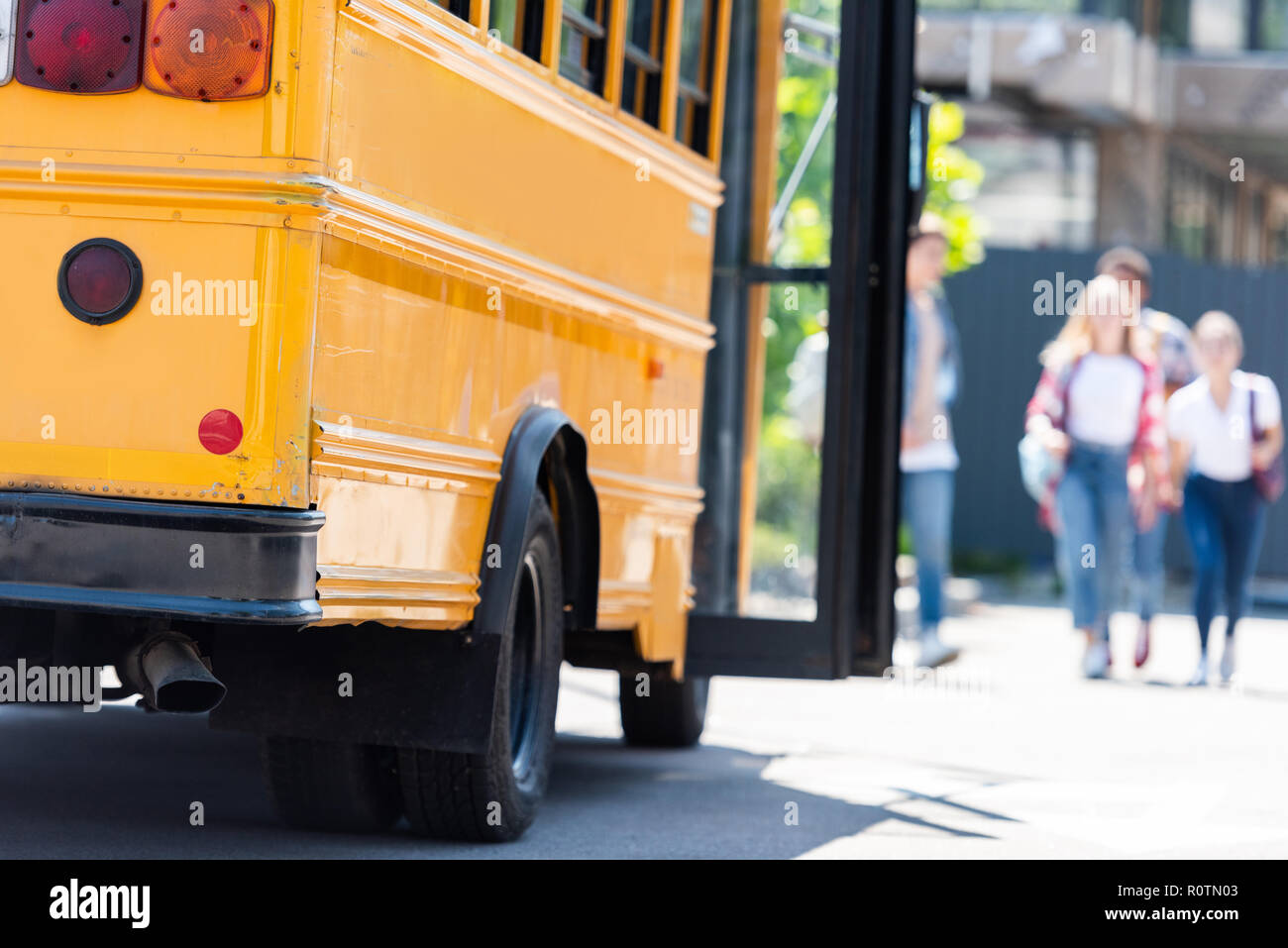 traditional american school bus with group of students walking blurred ...