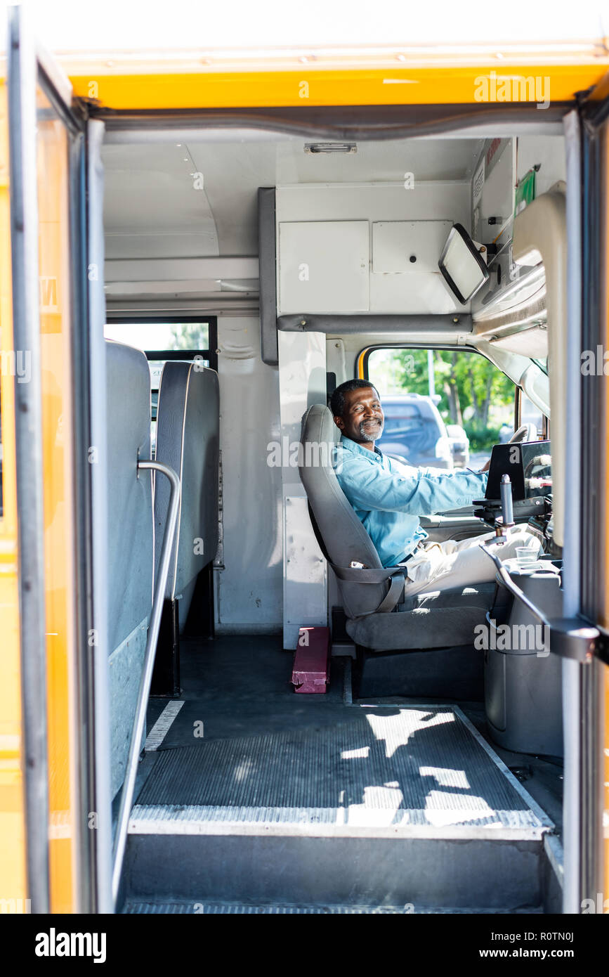 happy mature african american driver sitting at bus and looking at ...