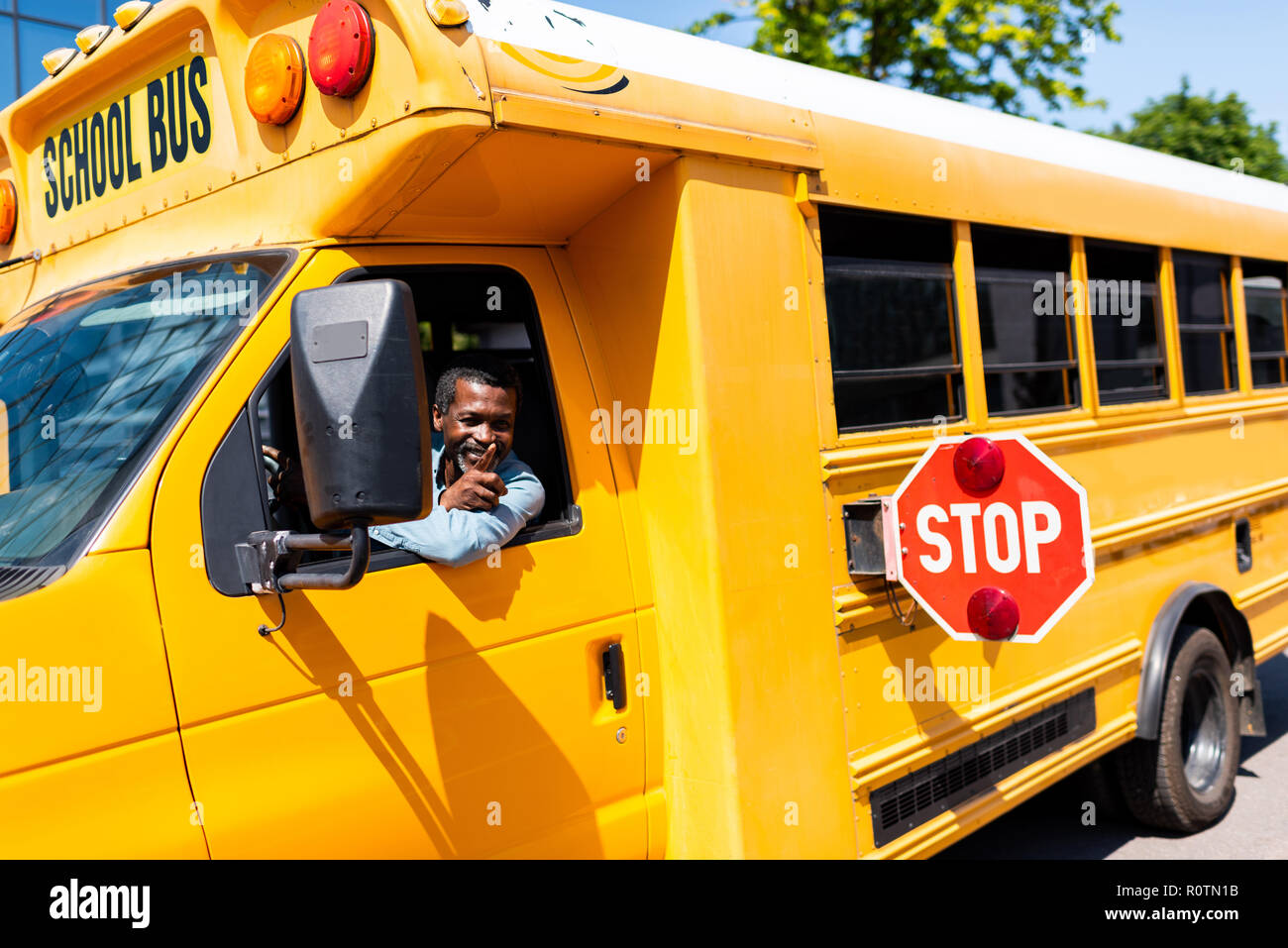 smiling mature african american bus driver looking out window and ...