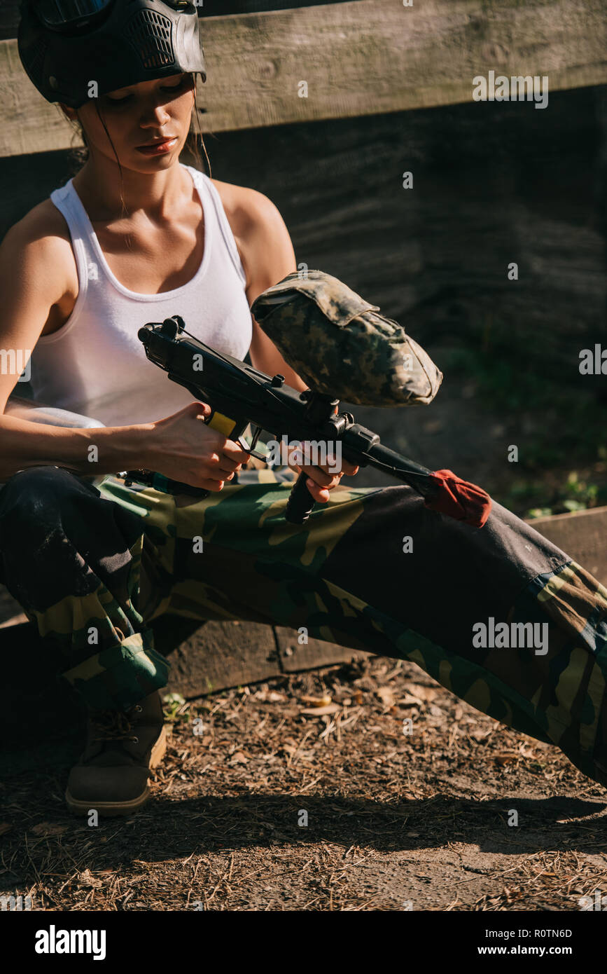 concentrated female paintballer in white singlet and goggle mask ...