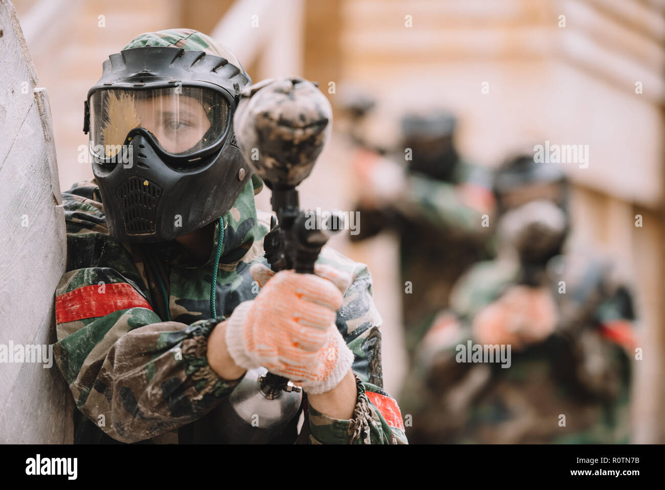 male paintballer in goggle mask covered by paintball splash aiming by ...