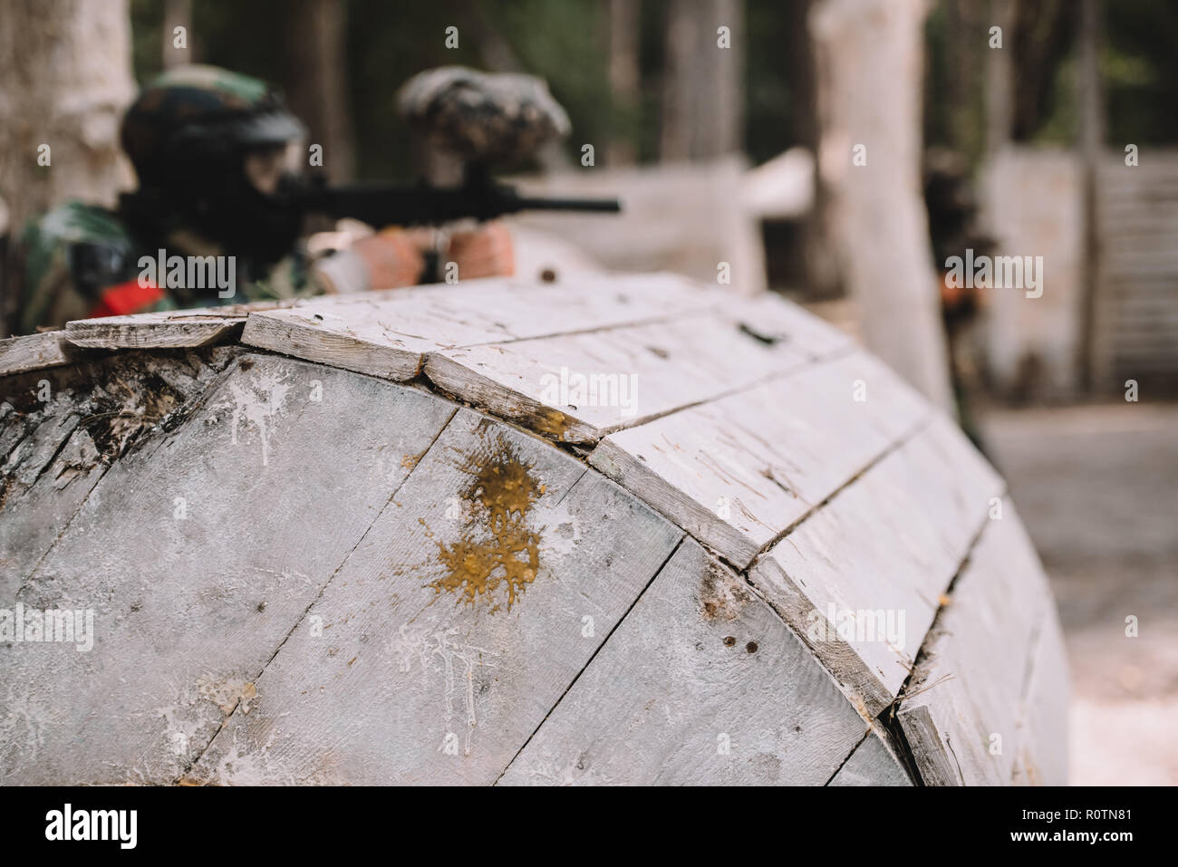 selective focus of paintball splashes on wooden barrel and paintball ...
