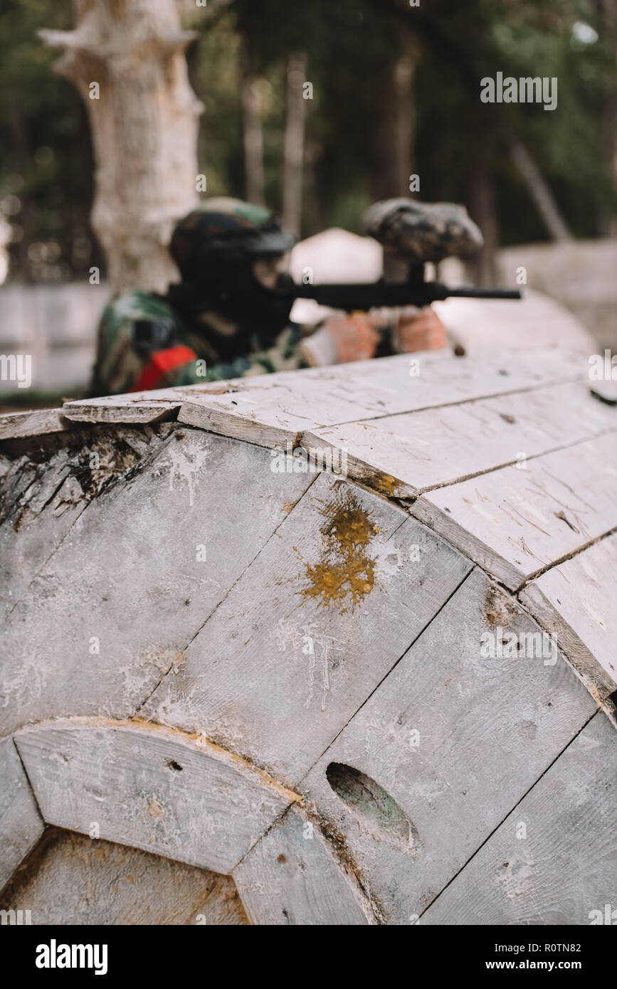 selective focus of paintball splashes on wooden barrel and paintball ...