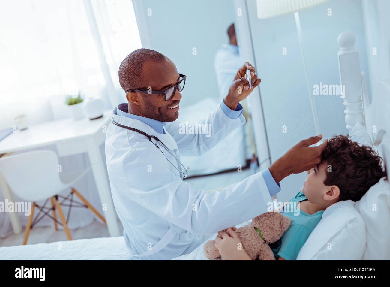 Smart male doctor checking his patients temperature Stock Photo - Alamy