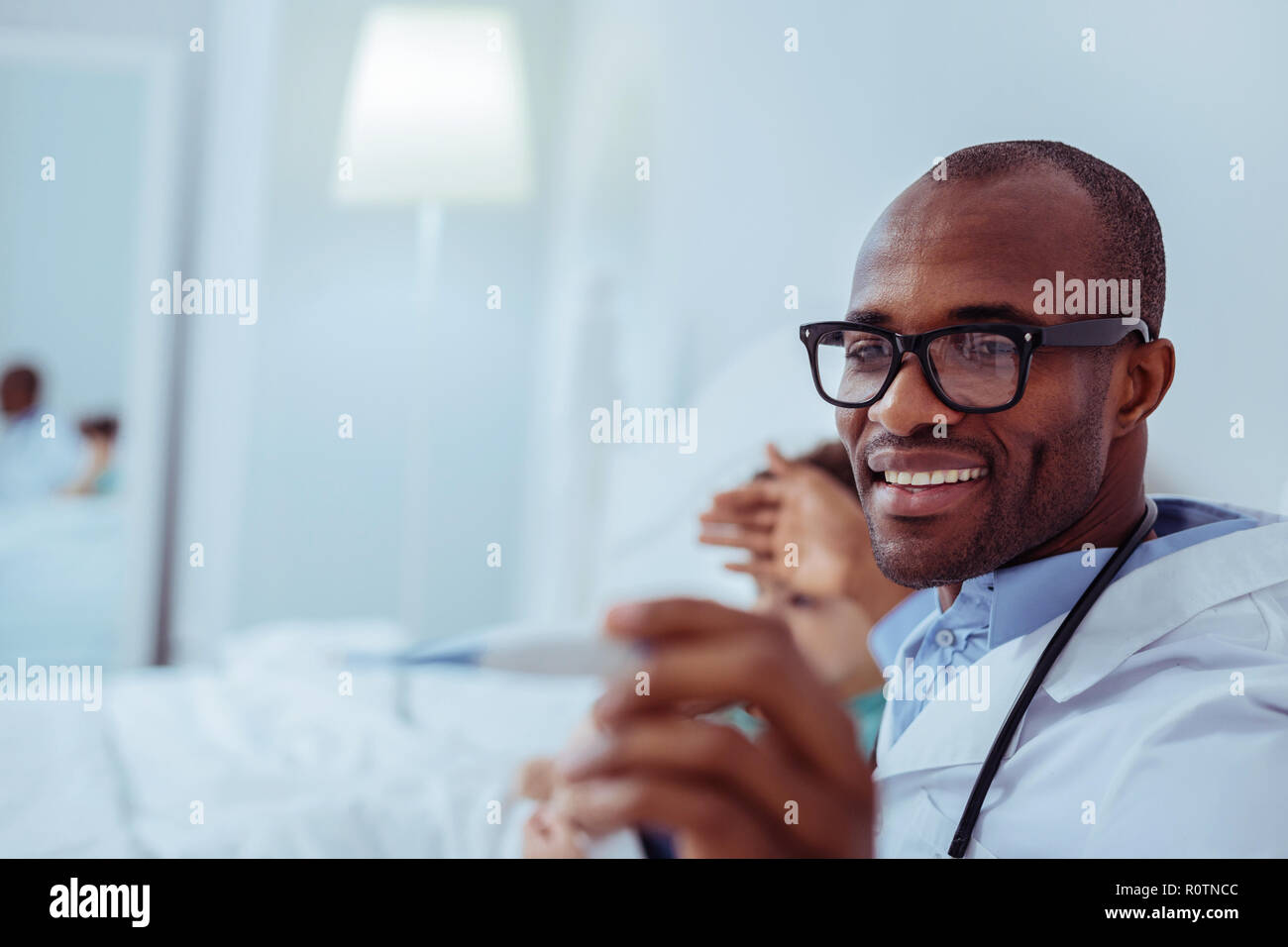Positive smiling doctor checking the body temperature Stock Photo - Alamy