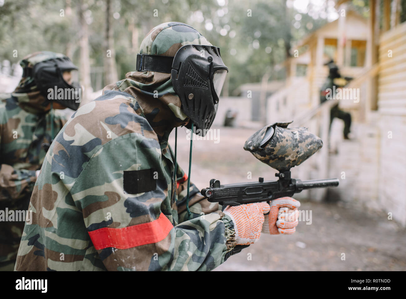 side view of male paintballer and his team in uniform and protective ...