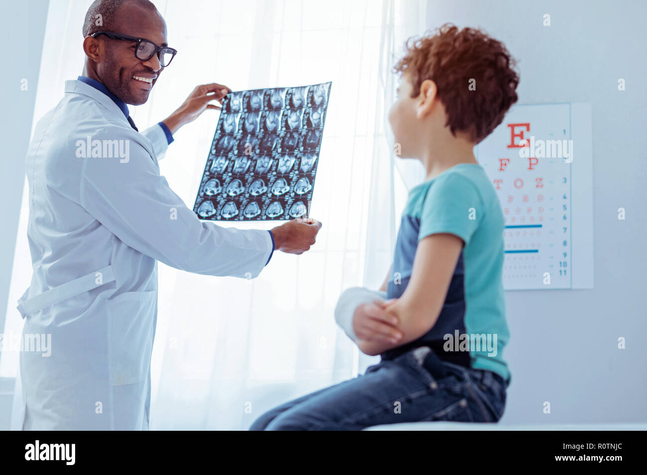 Positive friendly doctor looking at his patients xray image Stock Photo ...