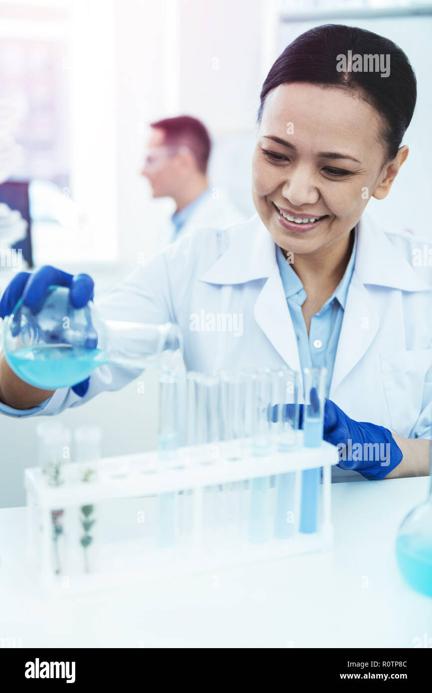 Happy nice woman pouring liquid in test tubes Stock Photo - Alamy