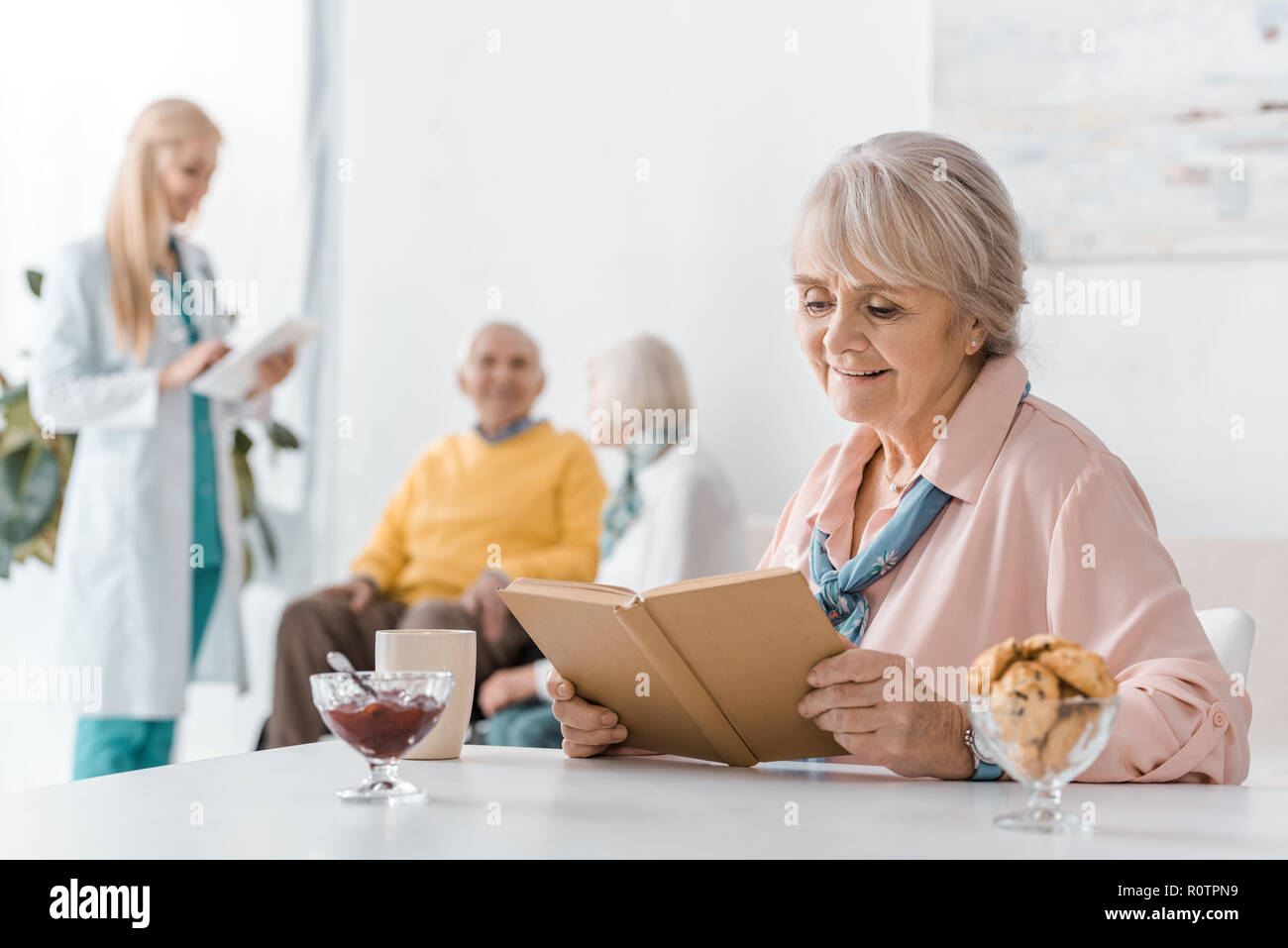 senior woman reading book while female doctor examining people Stock ...