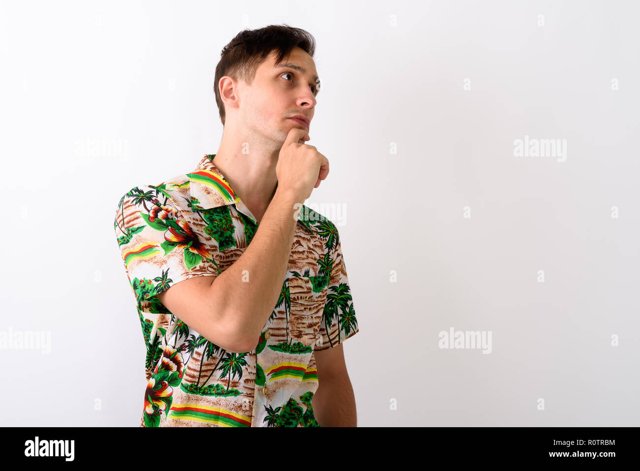Studio shot of young handsome tourist man thinking while looking Stock ...