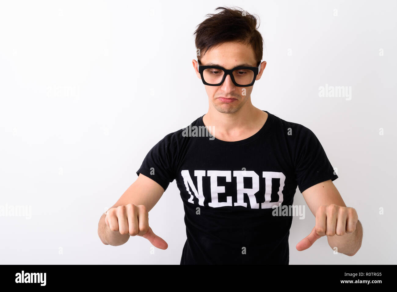 Studio shot of young nerd man looking sad and giving thumbs down Stock ...