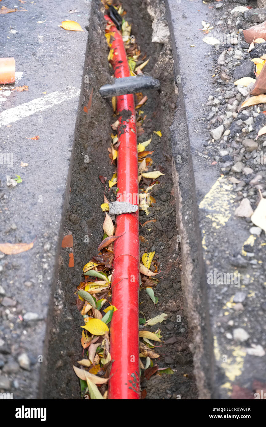 Underground electrical red cable duct in trench at construction ...