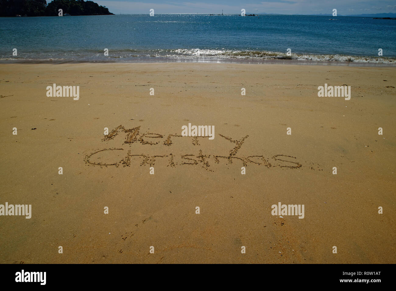 A sand message, Merry Christmas, hand written in the sand with the blue ...