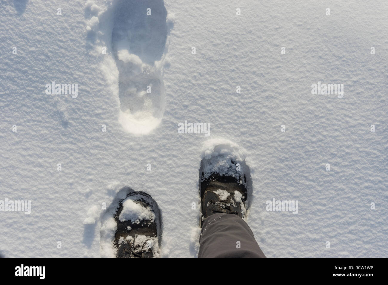 Winter scenery with human legs wearing boots and doing steps on a fresh ...