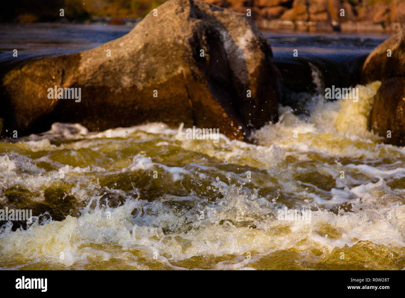 powerful stream of water goes around stone rapids with splashes and ...