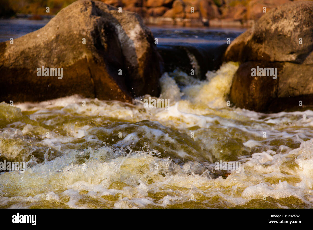 powerful stream of water goes around stone rapids with splashes and ...