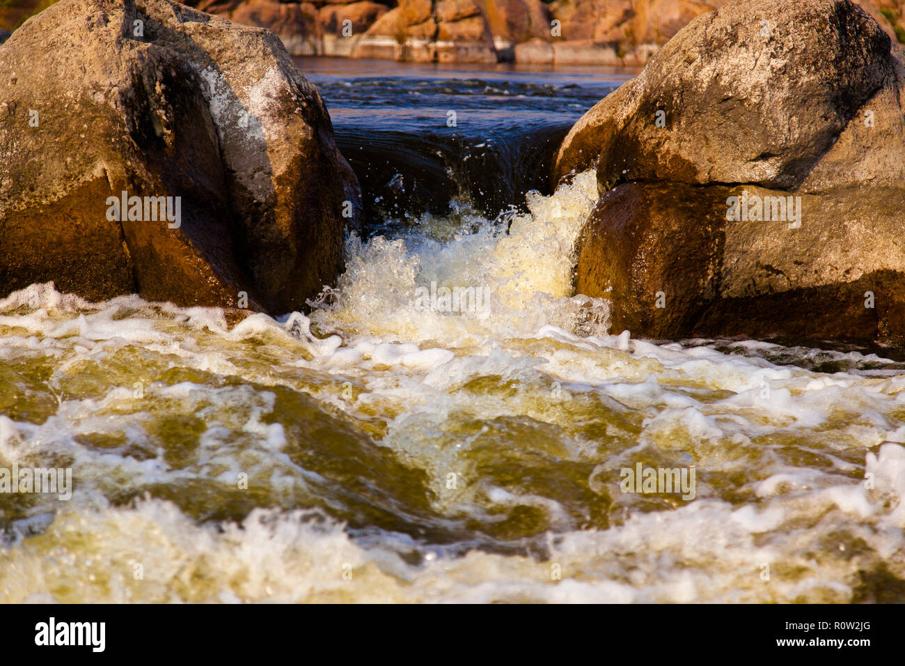 powerful stream of water goes around stone rapids with splashes and ...