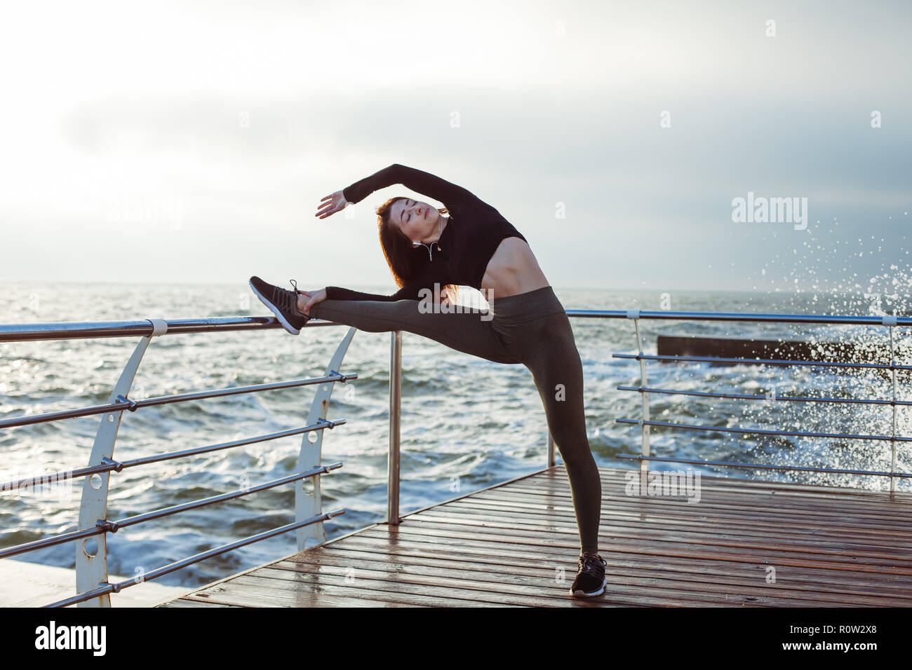 Fitness model athlete girl warm up stretching her hamstrings, leg and ...