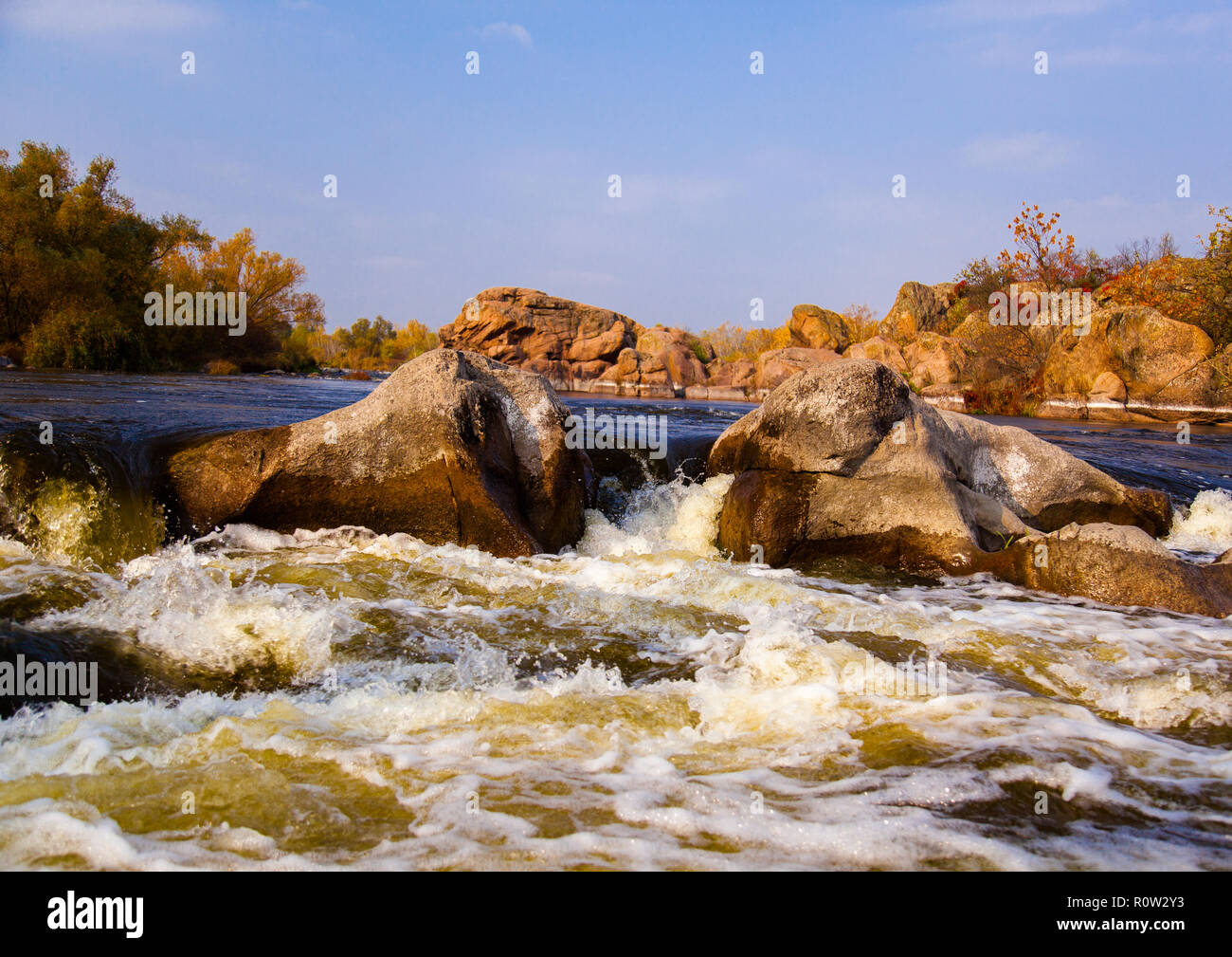 powerful stream of water goes around stone rapids with splashes and ...