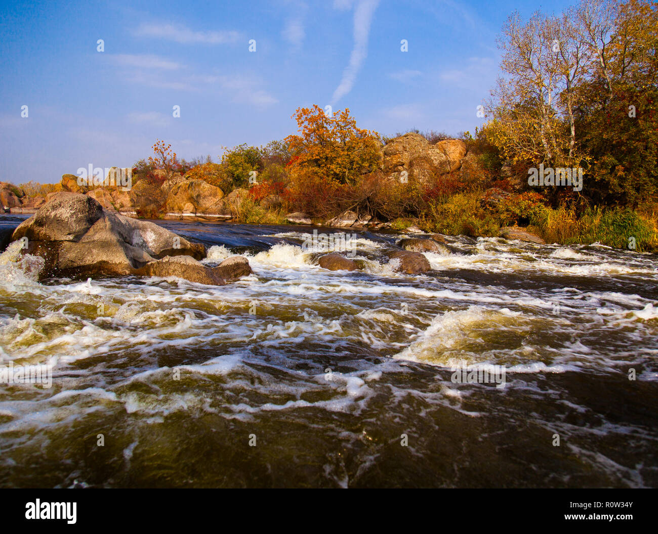 powerful stream of water goes around stone rapids with splashes and ...