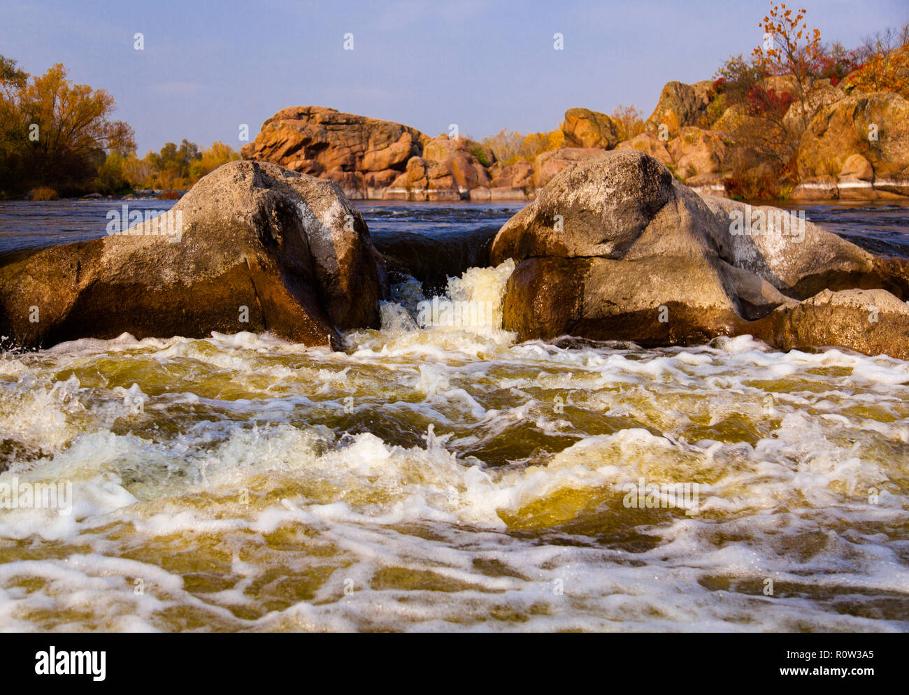 powerful stream of water goes around stone rapids with splashes and ...