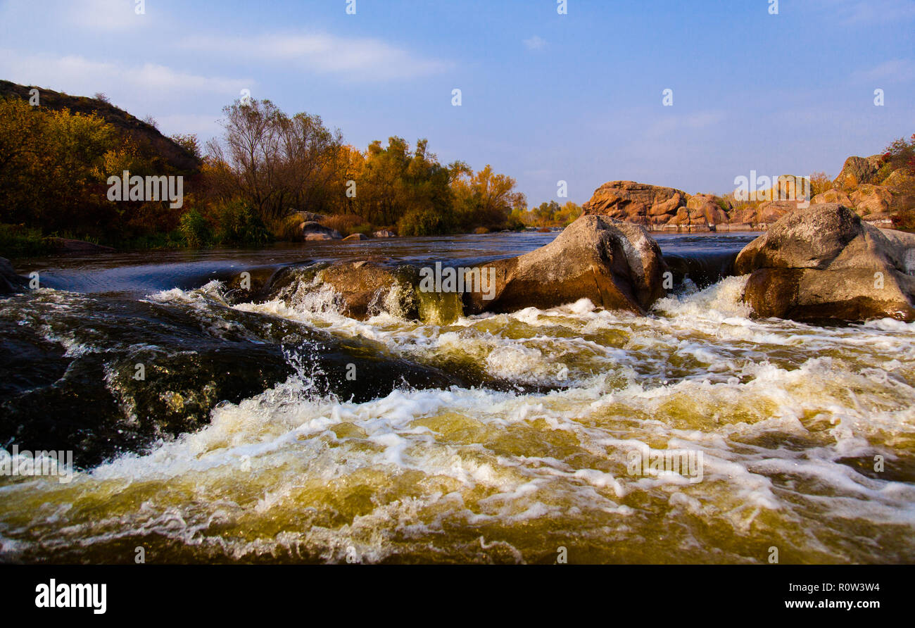 powerful stream of water goes around stone rapids with splashes and ...