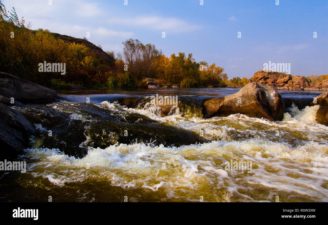powerful stream of water goes around stone rapids with splashes and ...
