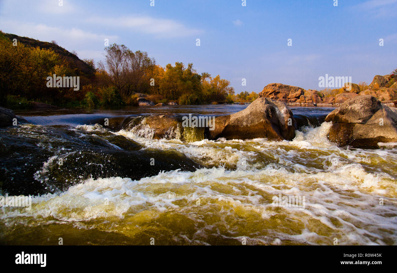 powerful stream of water goes around stone rapids with splashes and ...