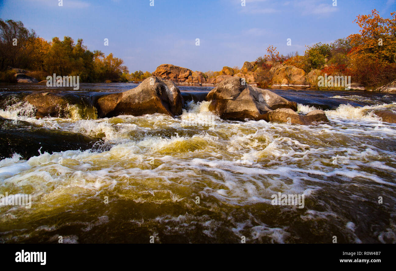 powerful stream of water goes around stone rapids with splashes and ...