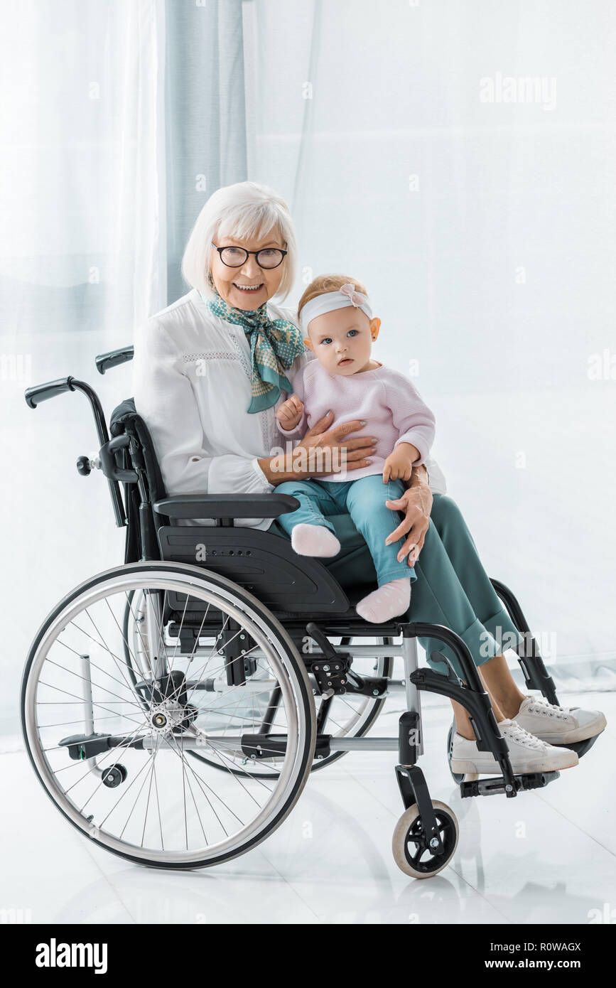 smiling grandmother in wheelchair holding small granddaughter Stock ...