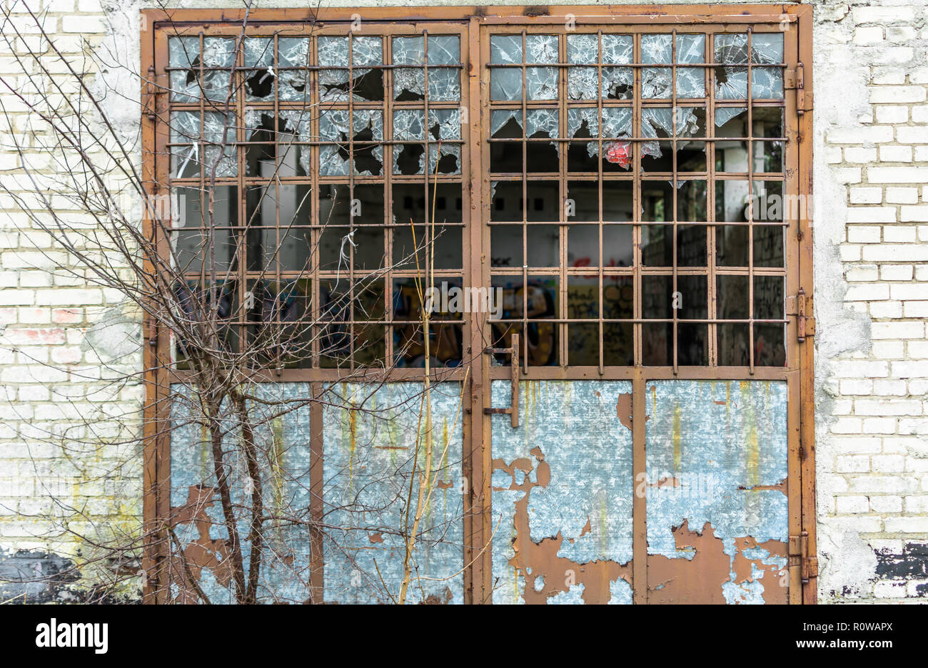 Old industrial factory wall of white bricks with damaged door and ...