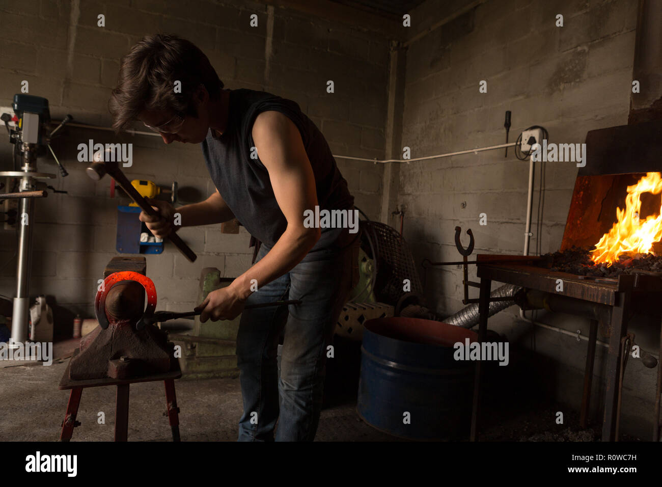 Female metalsmith molding horseshoe in factory Stock Photo - Alamy