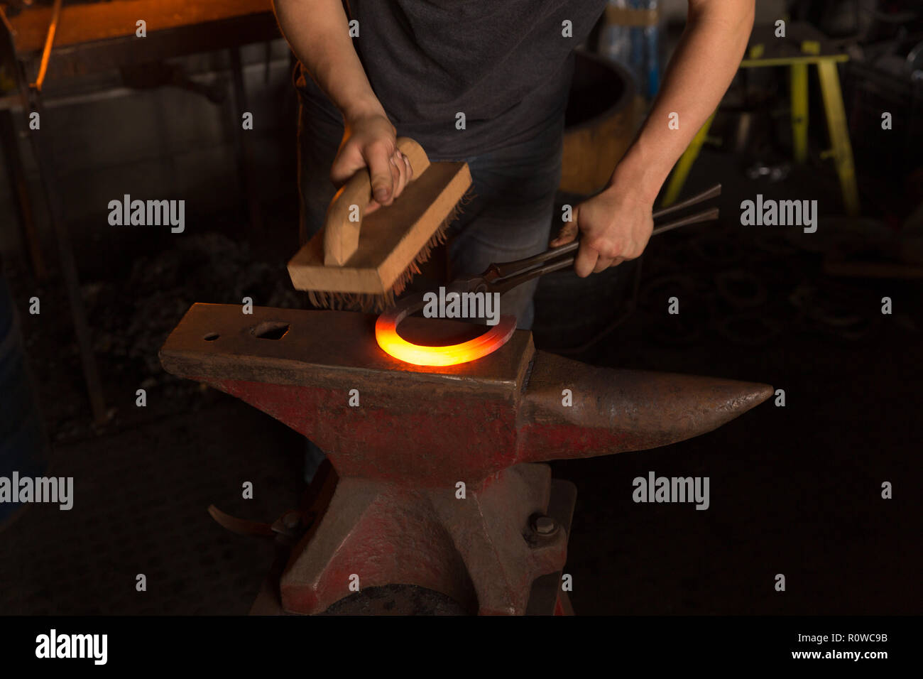 Female metalsmith brushing horseshoe in factory Stock Photo - Alamy
