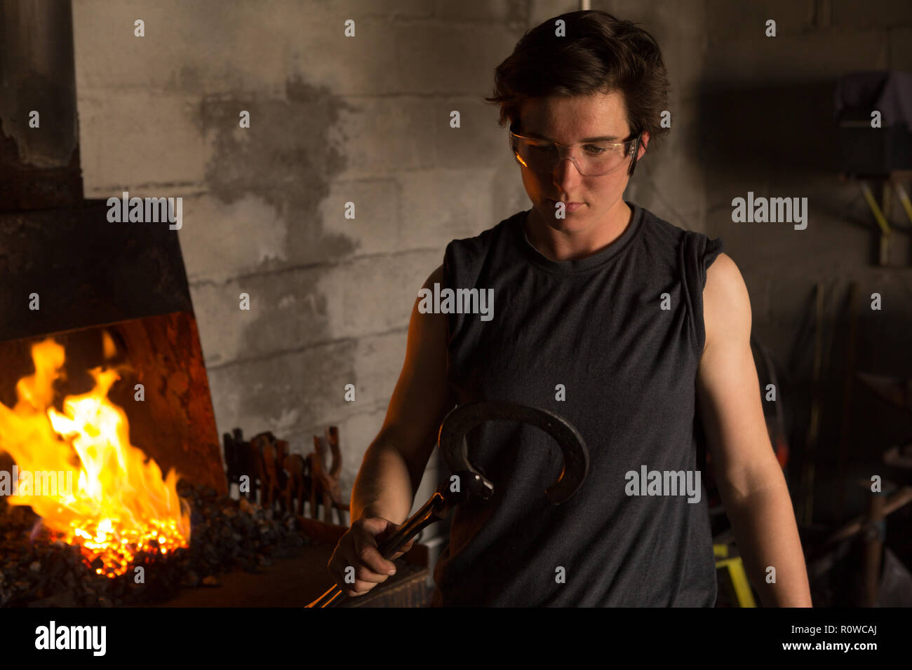 Female metalsmith holding horseshoe in factory Stock Photo - Alamy