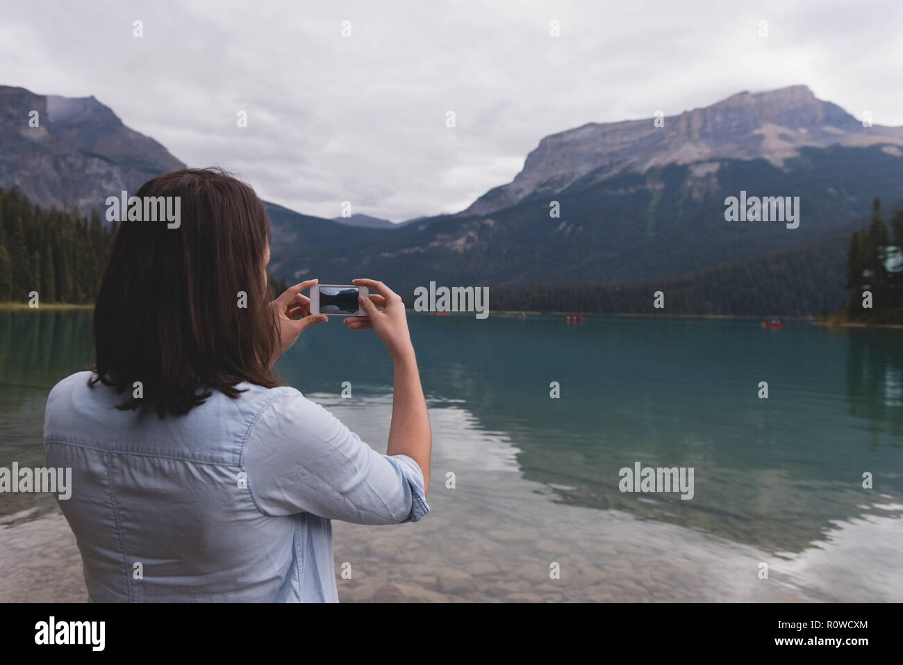 Woman clicking photos with mobile phone near lakeside Stock Photo - Alamy