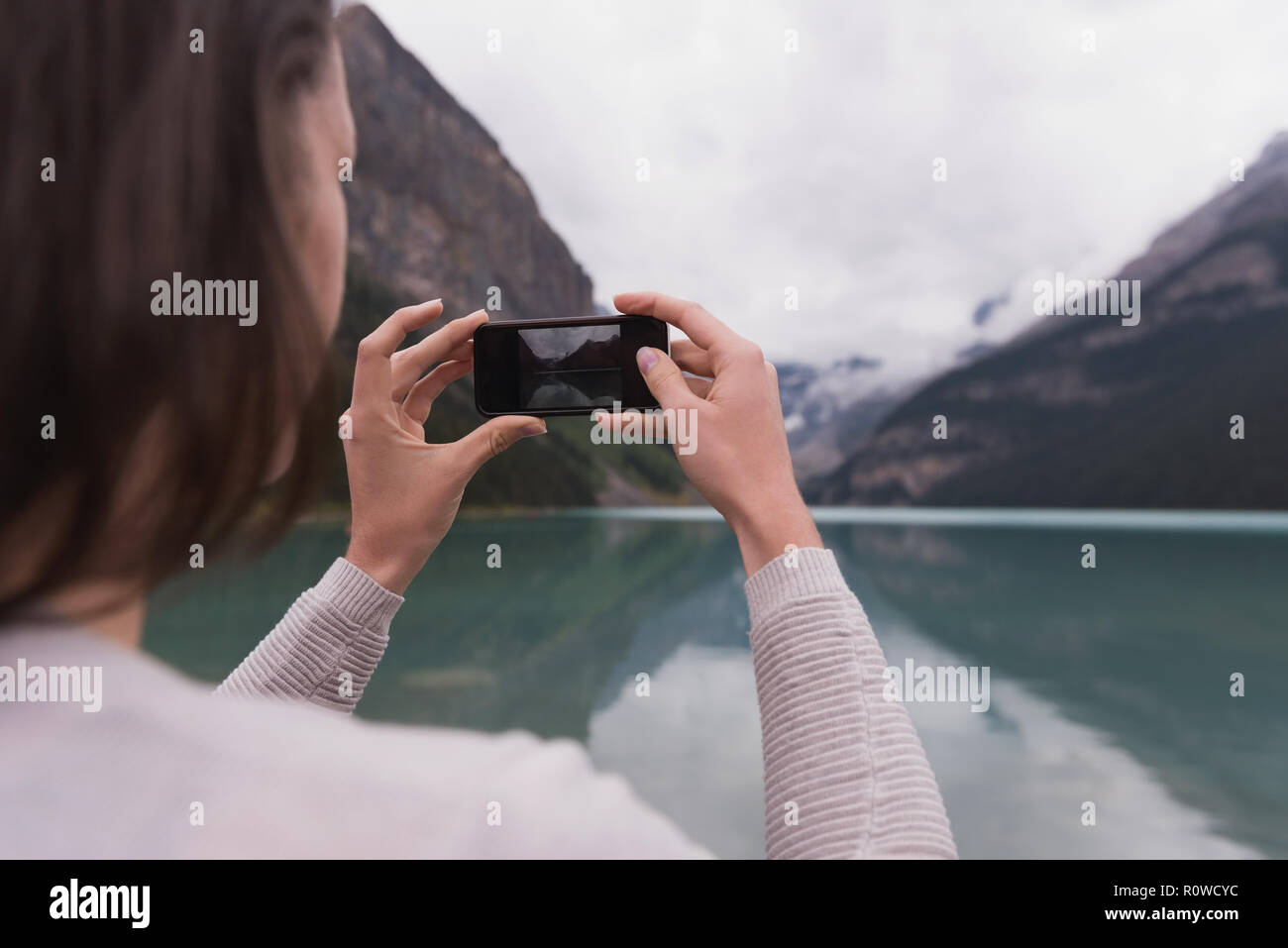 Woman clicking photos with mobile phone near lakeside Stock Photo - Alamy