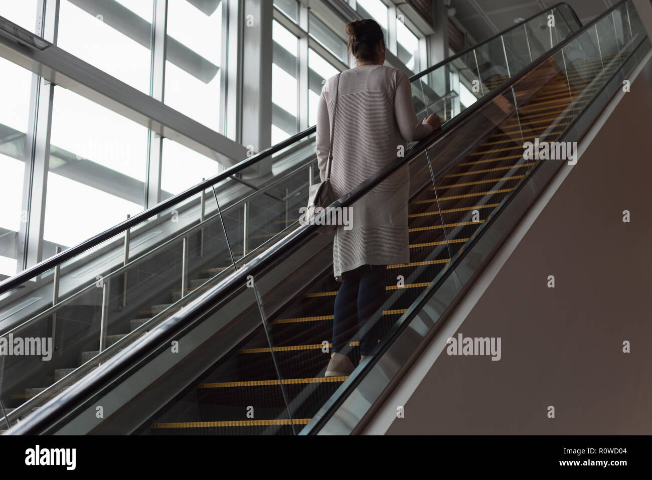 Woman moving up on escalator at railway station Stock Photo - Alamy