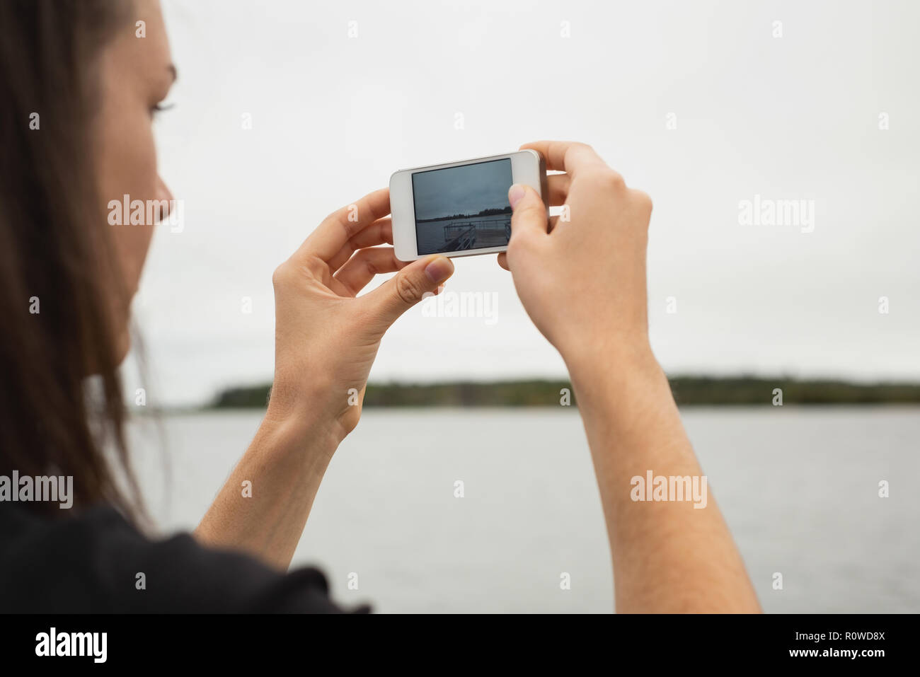 Woman clicking photos with mobile phone near riverside Stock Photo - Alamy