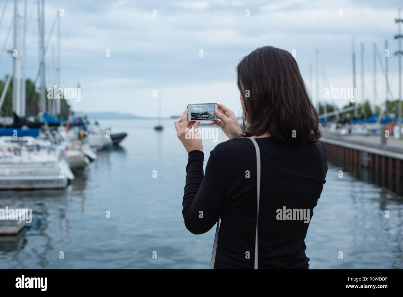 Woman clicking photos with mobile phone near harbor Stock Photo - Alamy