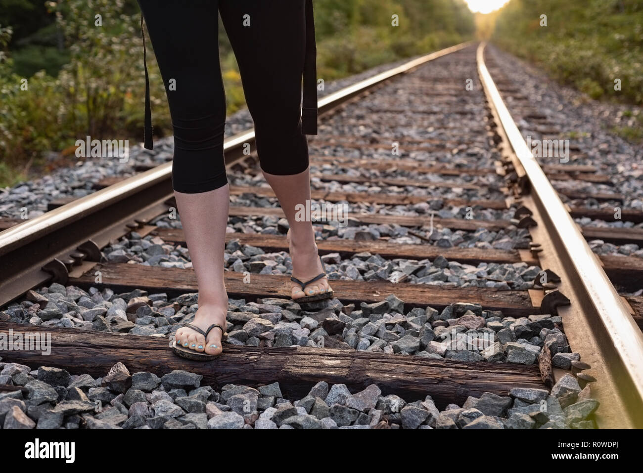 Woman walking on a railway track Stock Photo - Alamy